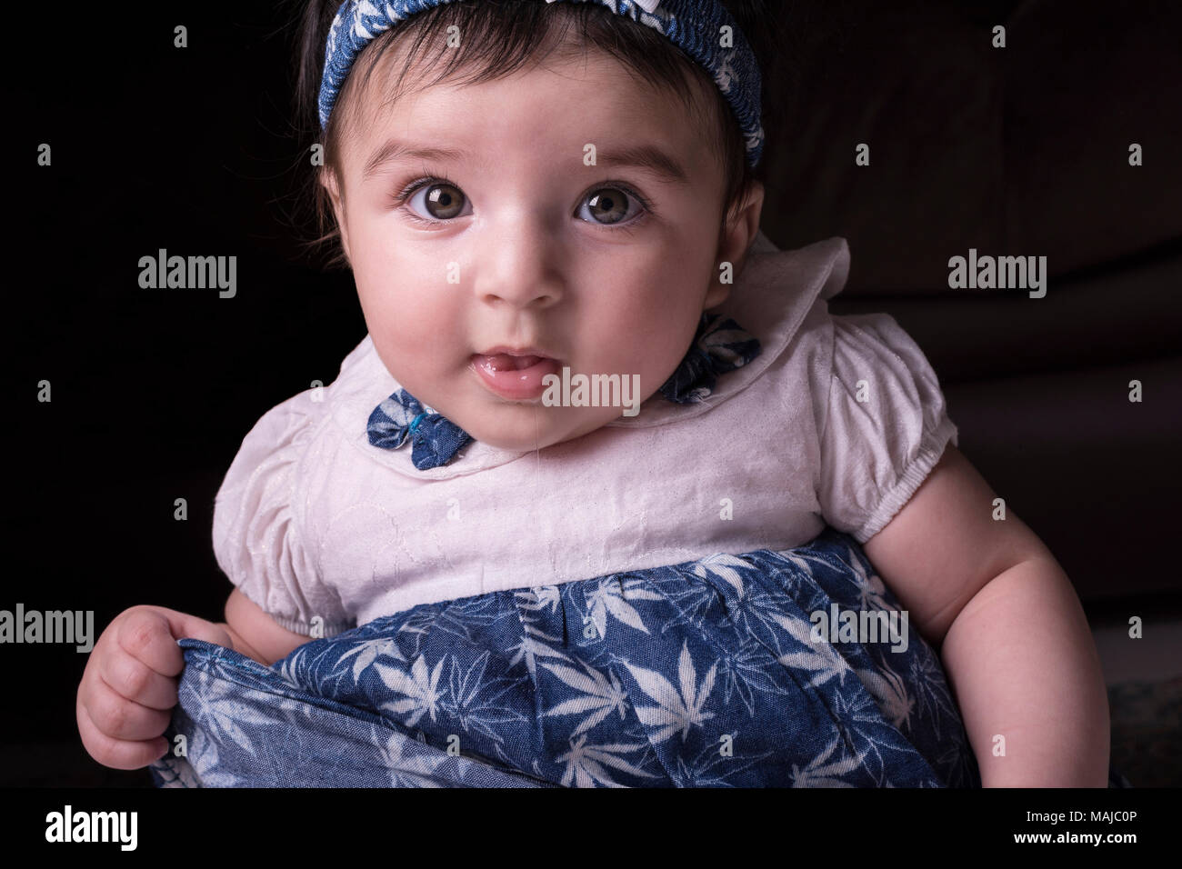 Close-up portrait of a 5 month old baby girl, drooling and directly ...