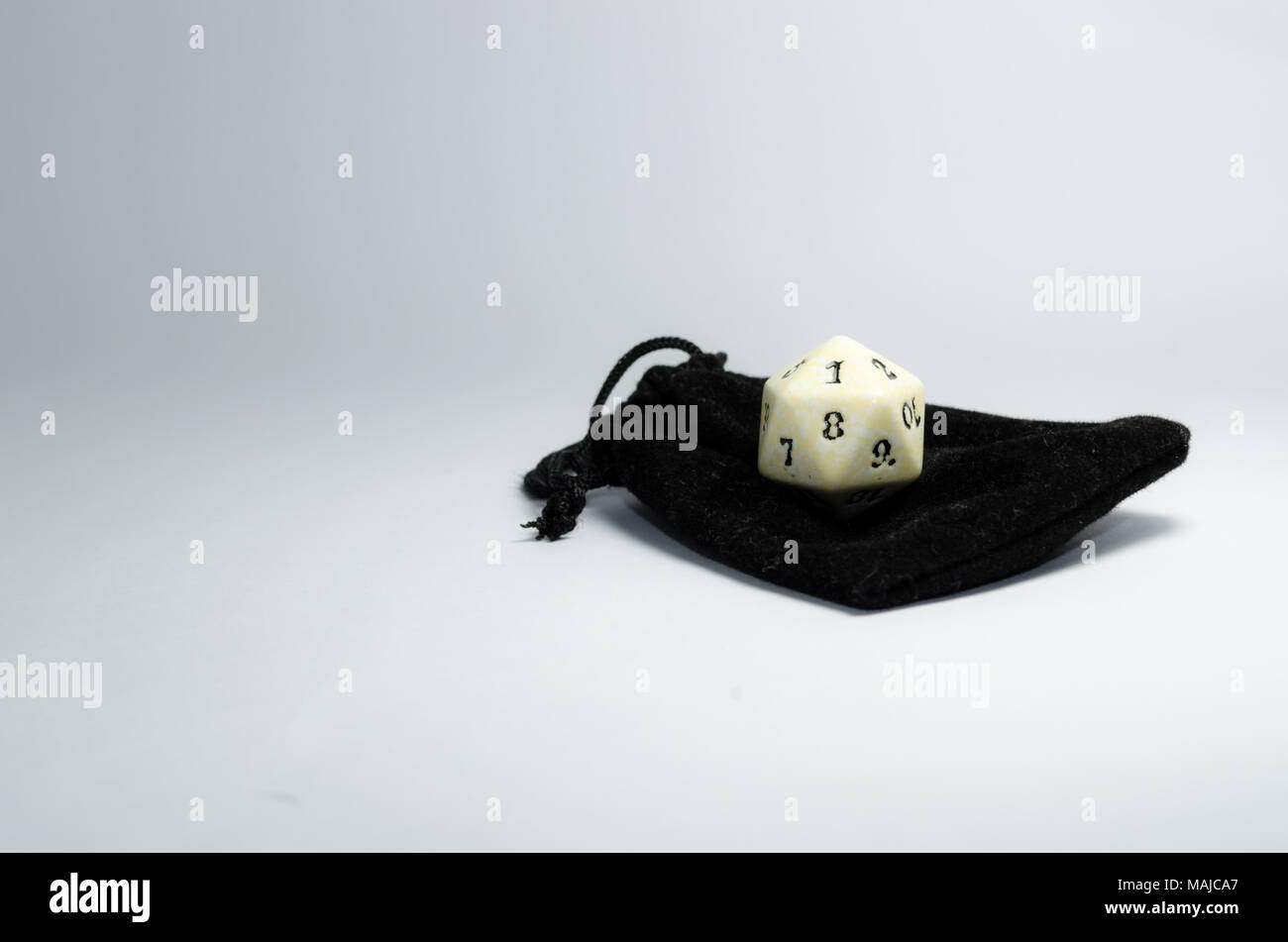 white twenty-sided dice on a small black purse on a white background ...