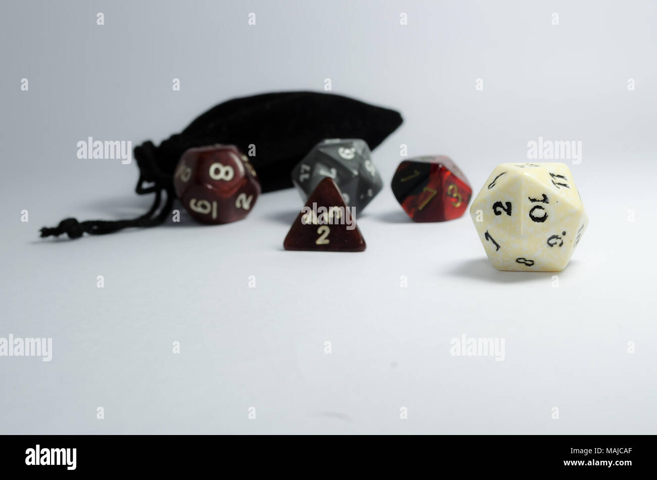 Some rpg dice and a small black bag, spread out in a white background ...