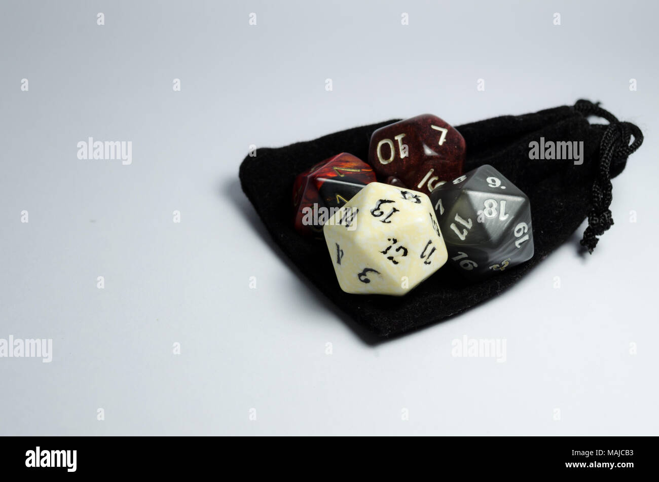 Some rpg dice and a small black bag, spread out in a white background ...