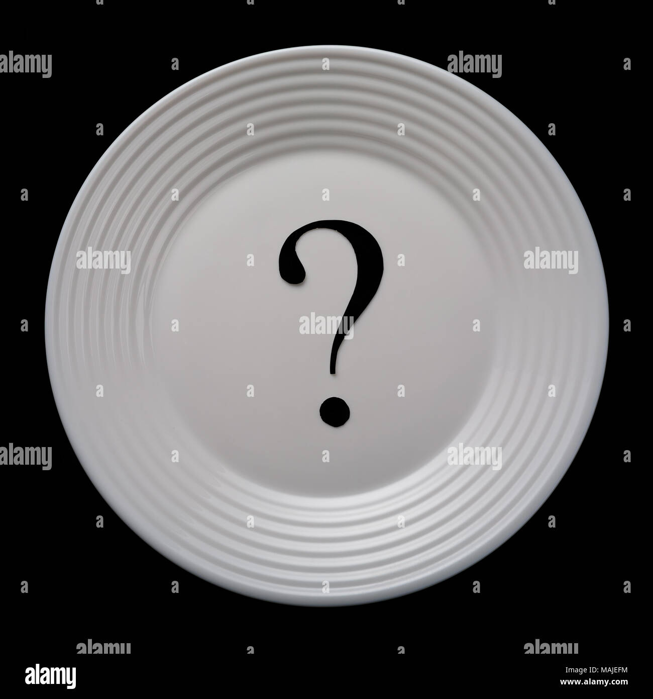 Empty white plate on a black background with a question mark, top view ...