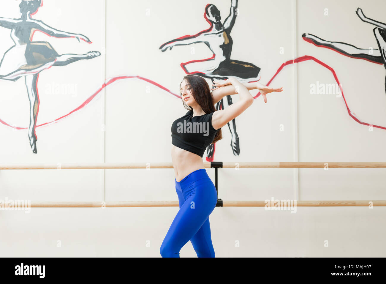 Cute young girl wearing black top and blue pants doing physical ...
