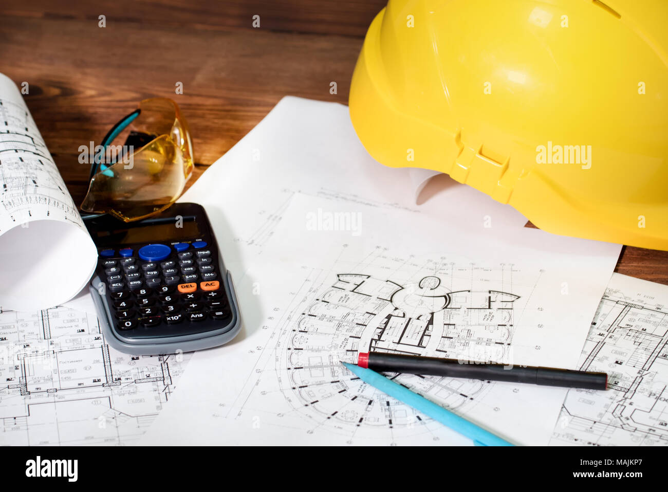 Construction plot/drawing, black calculator, blue pencil, yellow helmet ...