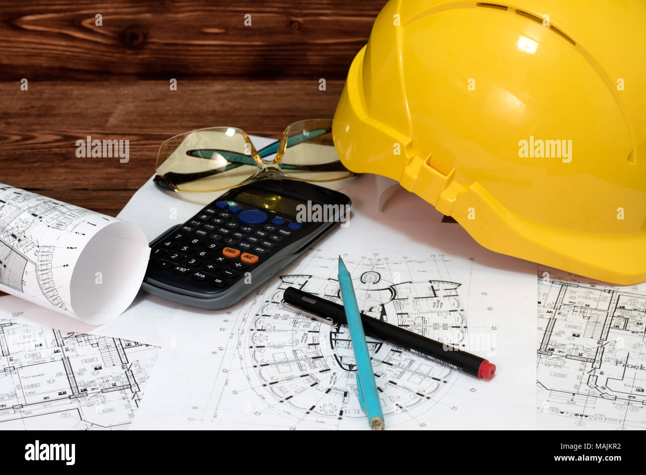Construction plot/drawing, black calculator, blue pencil, yellow helmet ...