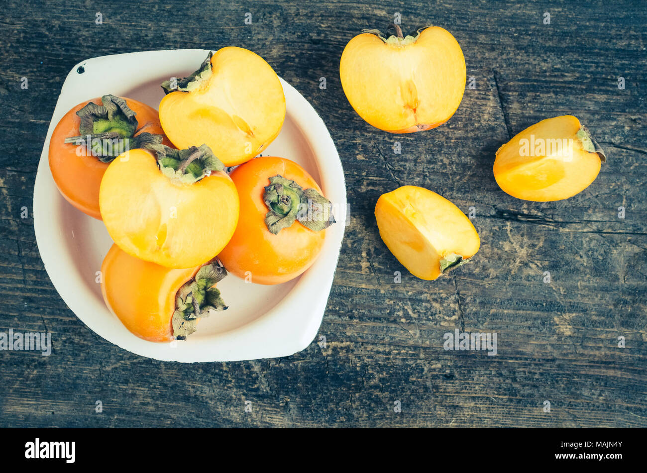Slice of ripe delicious fresh persimmon kaki fruit in white metal plate ...