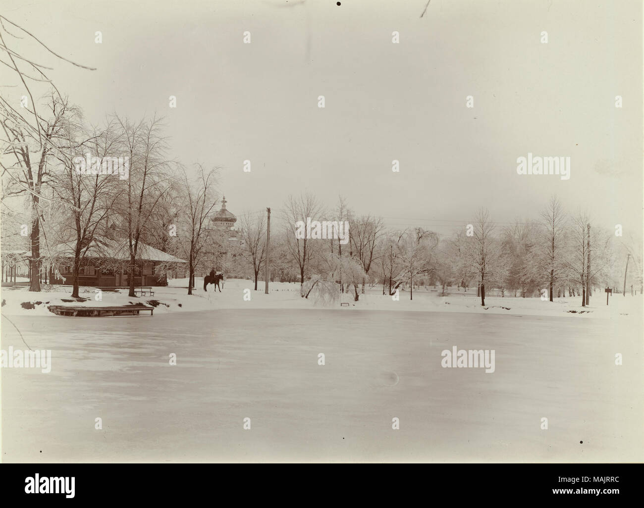 Title: Forest Park in winter snow; showing dock at lake, boathouse, man ...