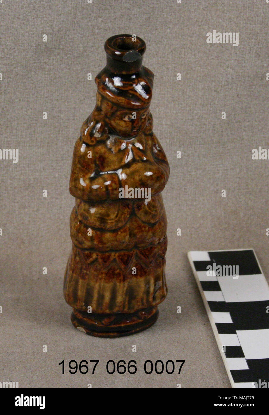 Lady-shaped ceramic toilet bottle. Lady wears hand muff and ankle ...