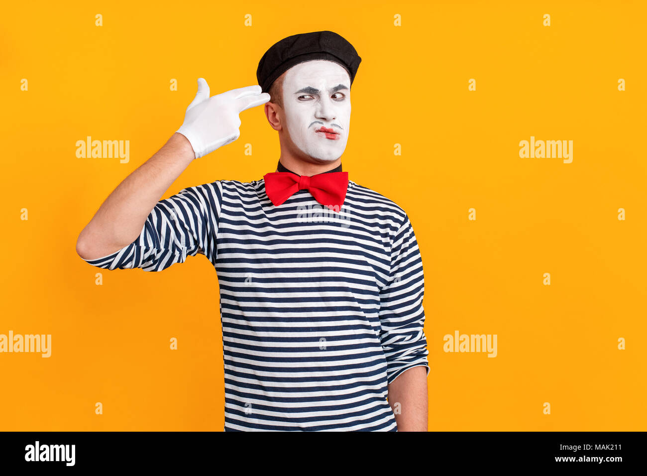 Mime man put to the temple gun. Emotions and feelings concept. Indoor ...