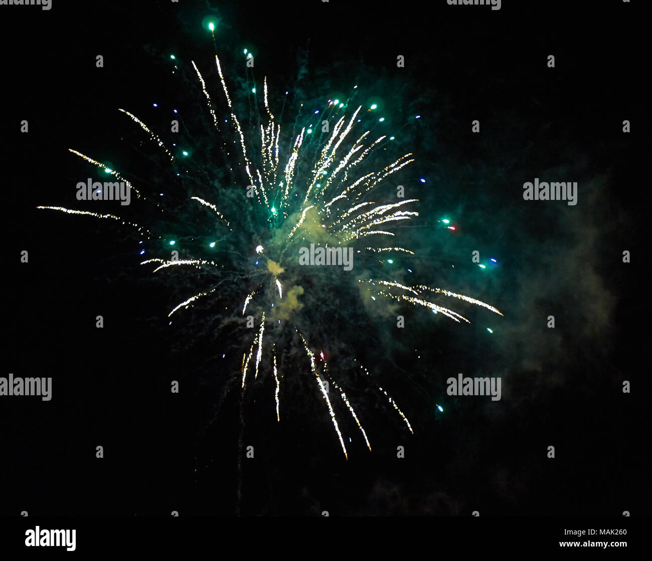 Colorful bright green fireworks and smoke in the night sky close-up ...