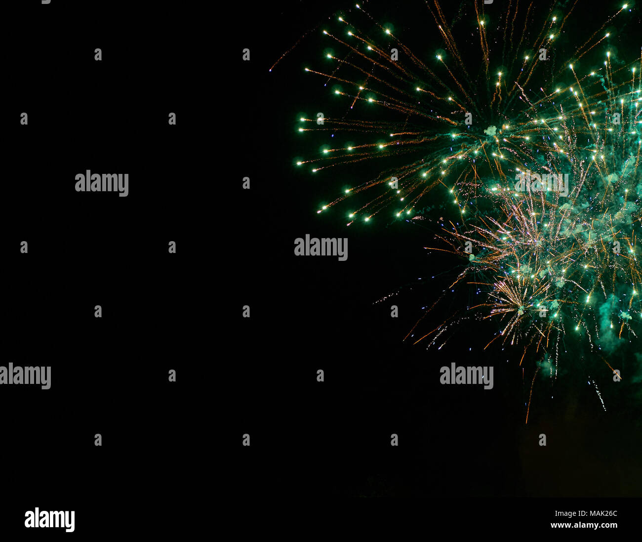 Colorful bright green fireworks and smoke in the night sky close-up ...