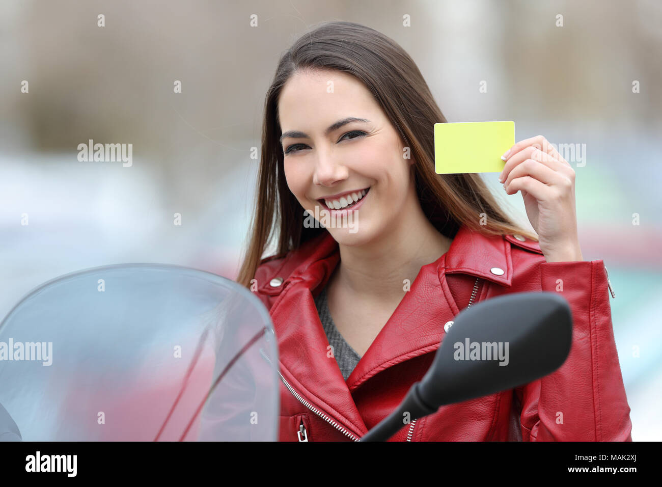 Happy biker showing a credit card or driving license on a motorbike on ...