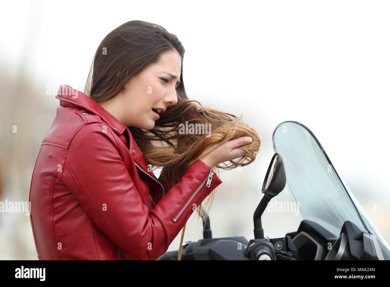 Portrait of a sad biker woman complaining about tangled hair after a ...