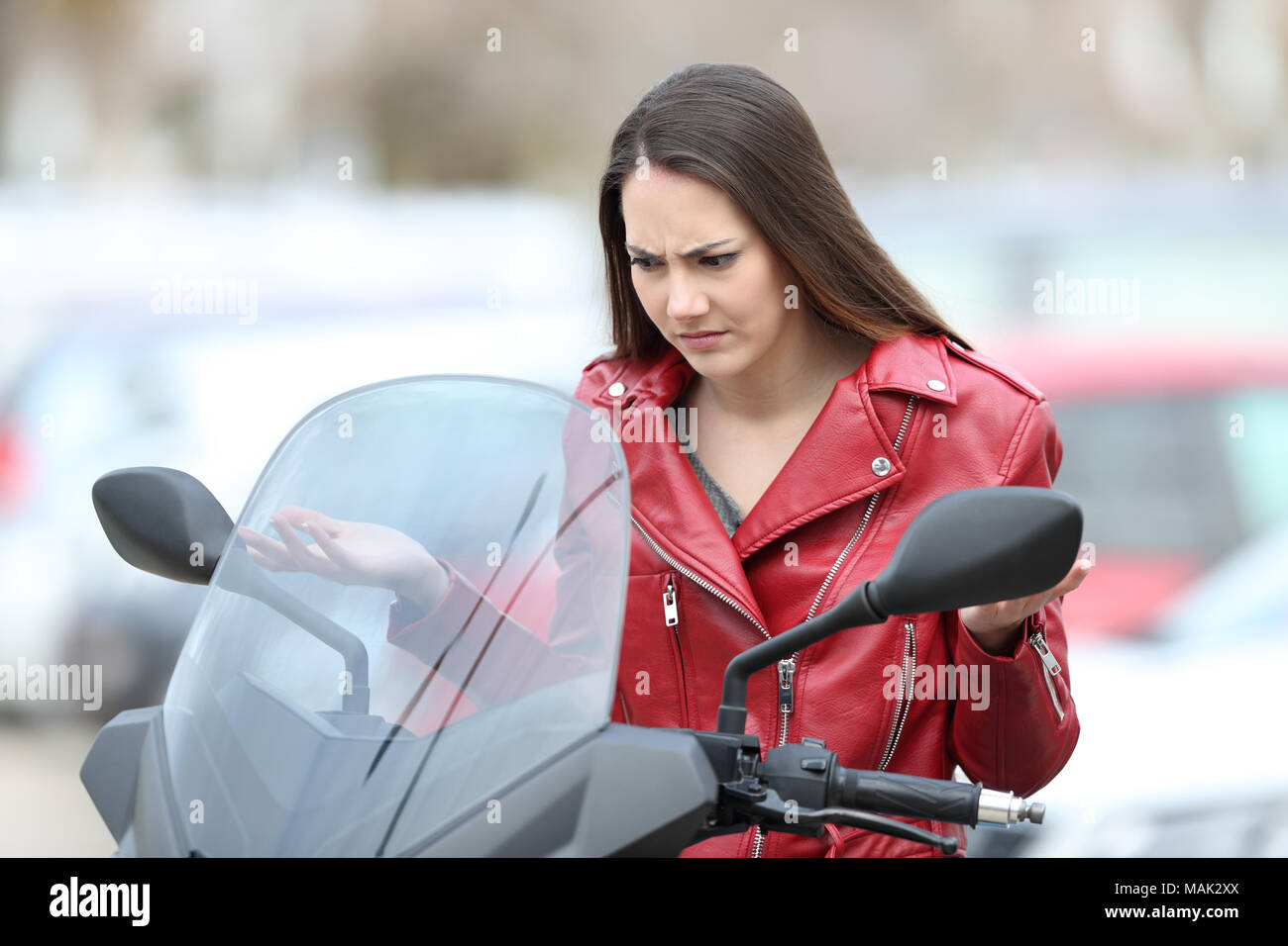 Portrait of a confused biker looking at broken down motorbike on the ...