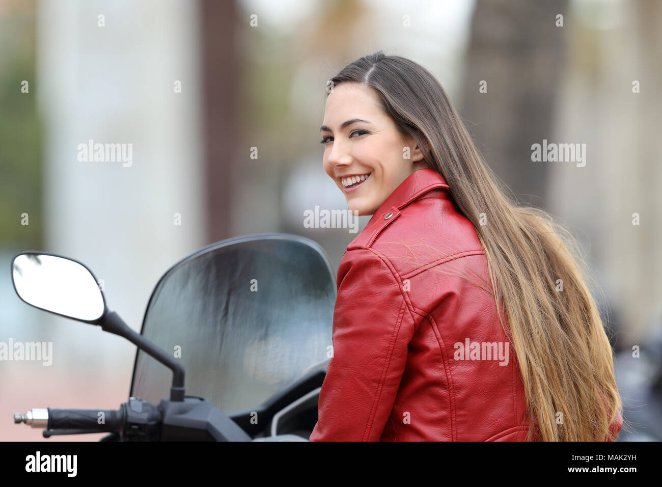Portrait of a happy biker looking at you on a motorbike on the street ...