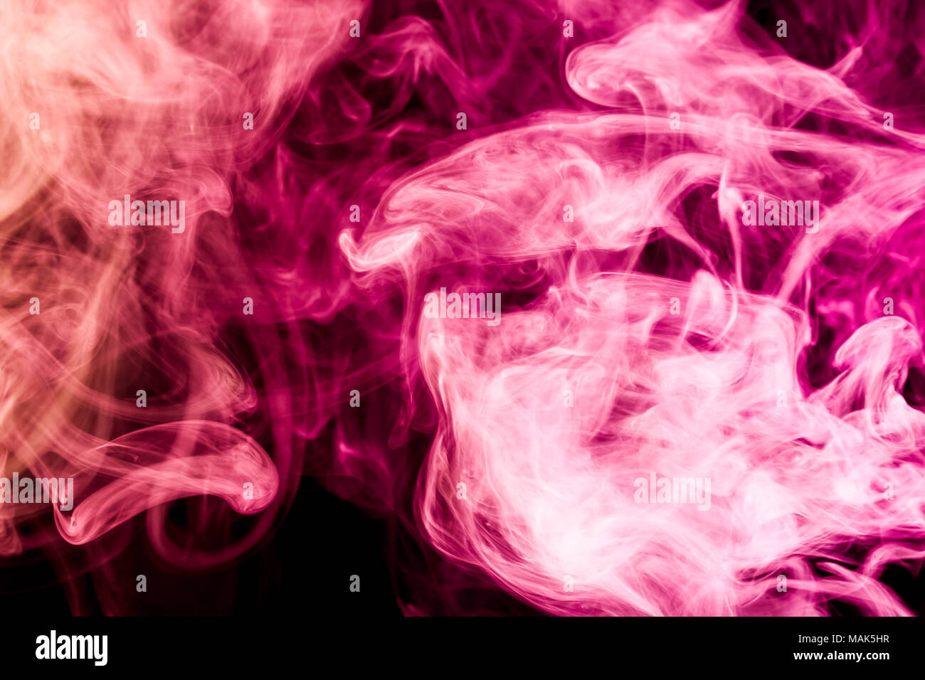 Thick colorful smoke of pink and purple on a black isolated background ...