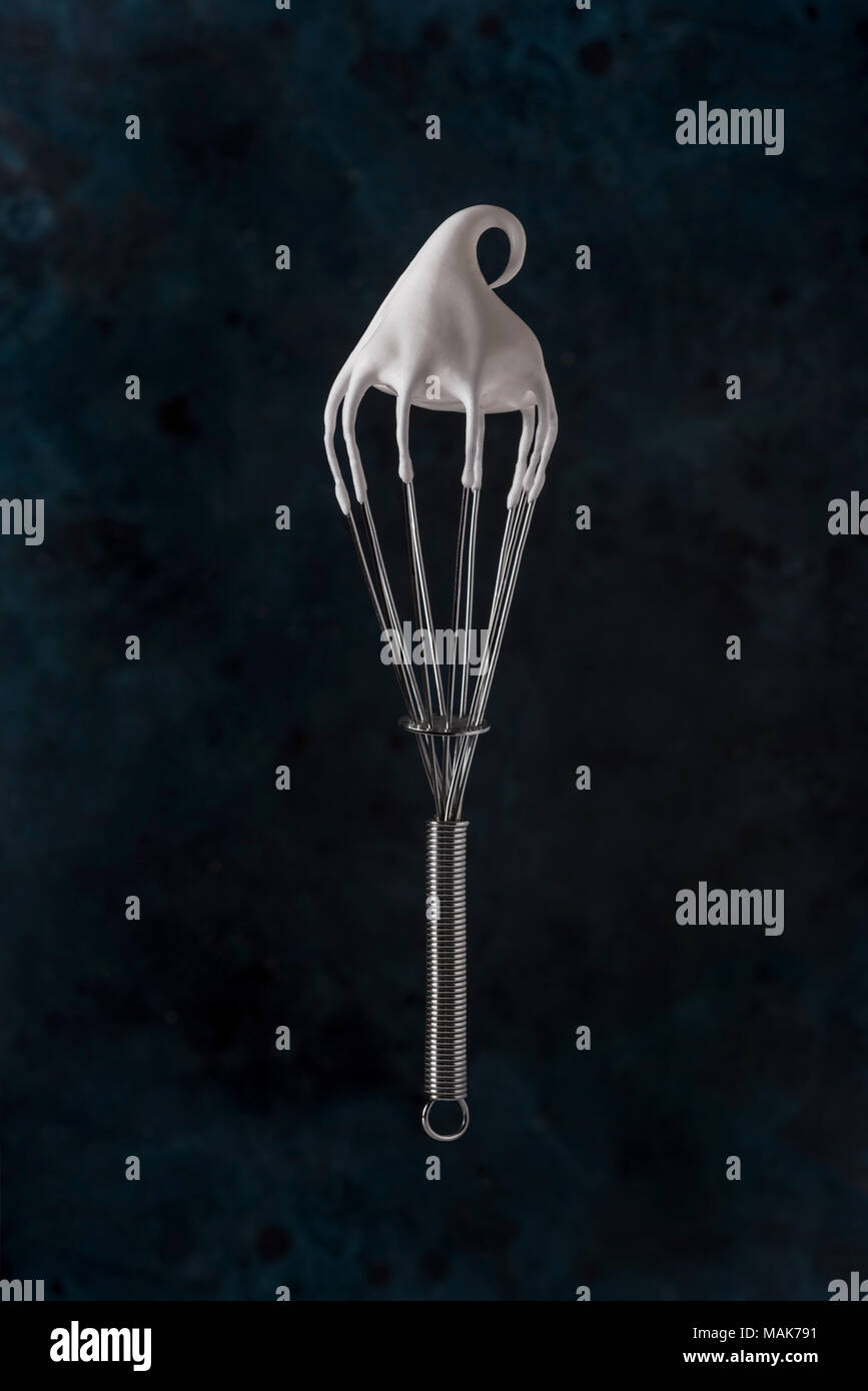 Whisk with meringue cream over dark blue background Stock Photo - Alamy