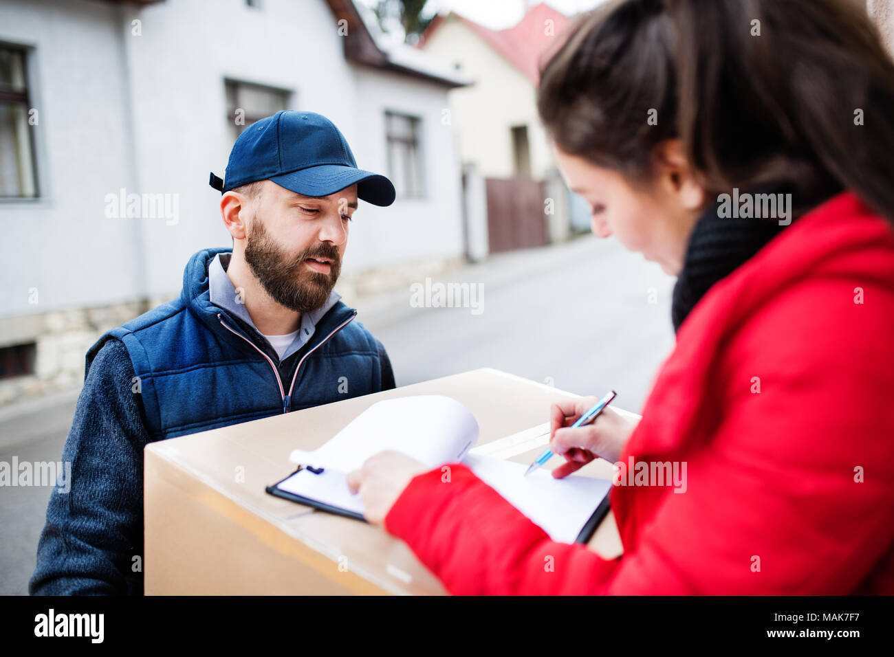 Woman receiving parcel from delivery man at the door Stock Photo - Alamy