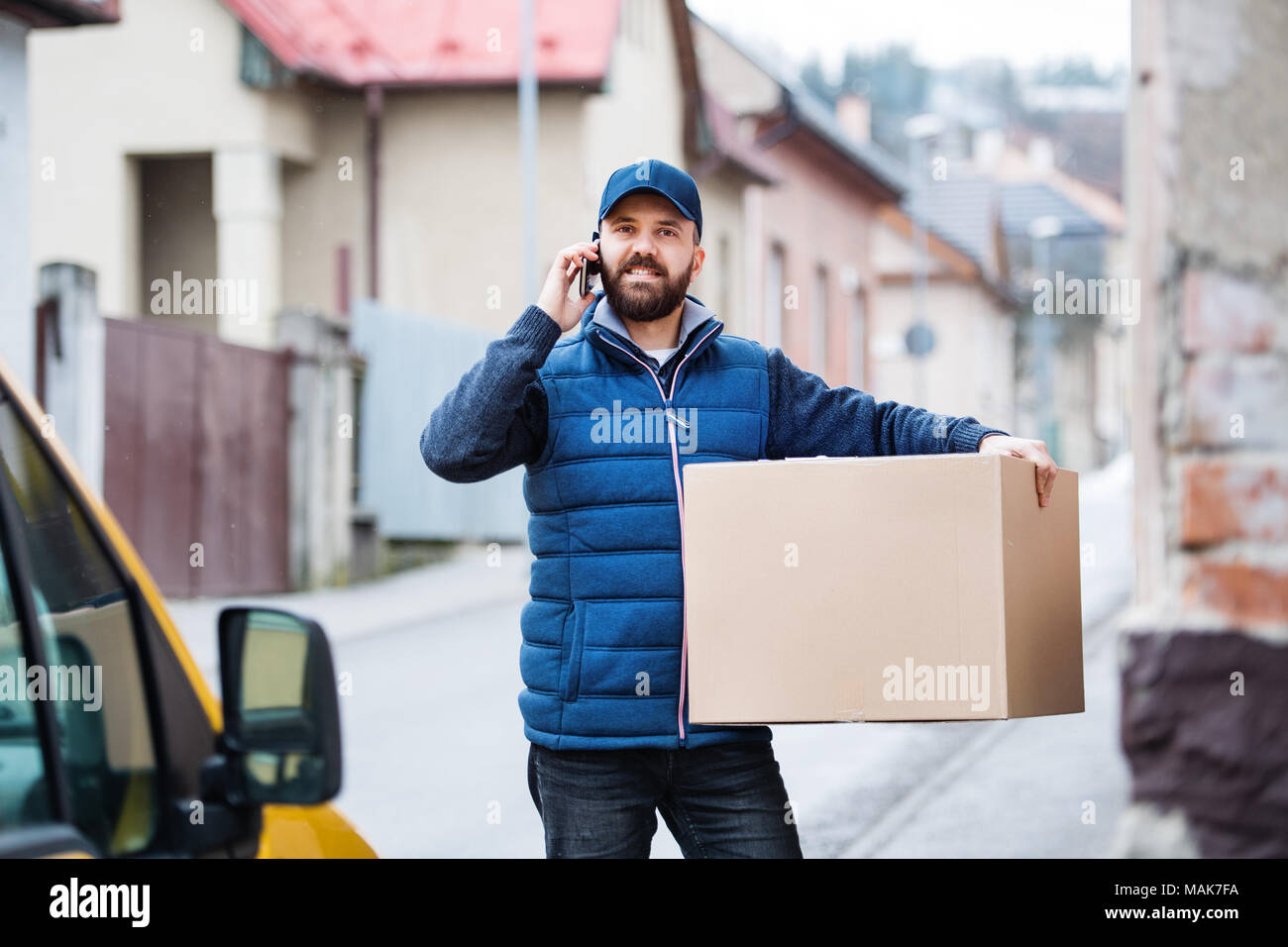 Delivery man with a parcel box on the street Stock Photo - Alamy