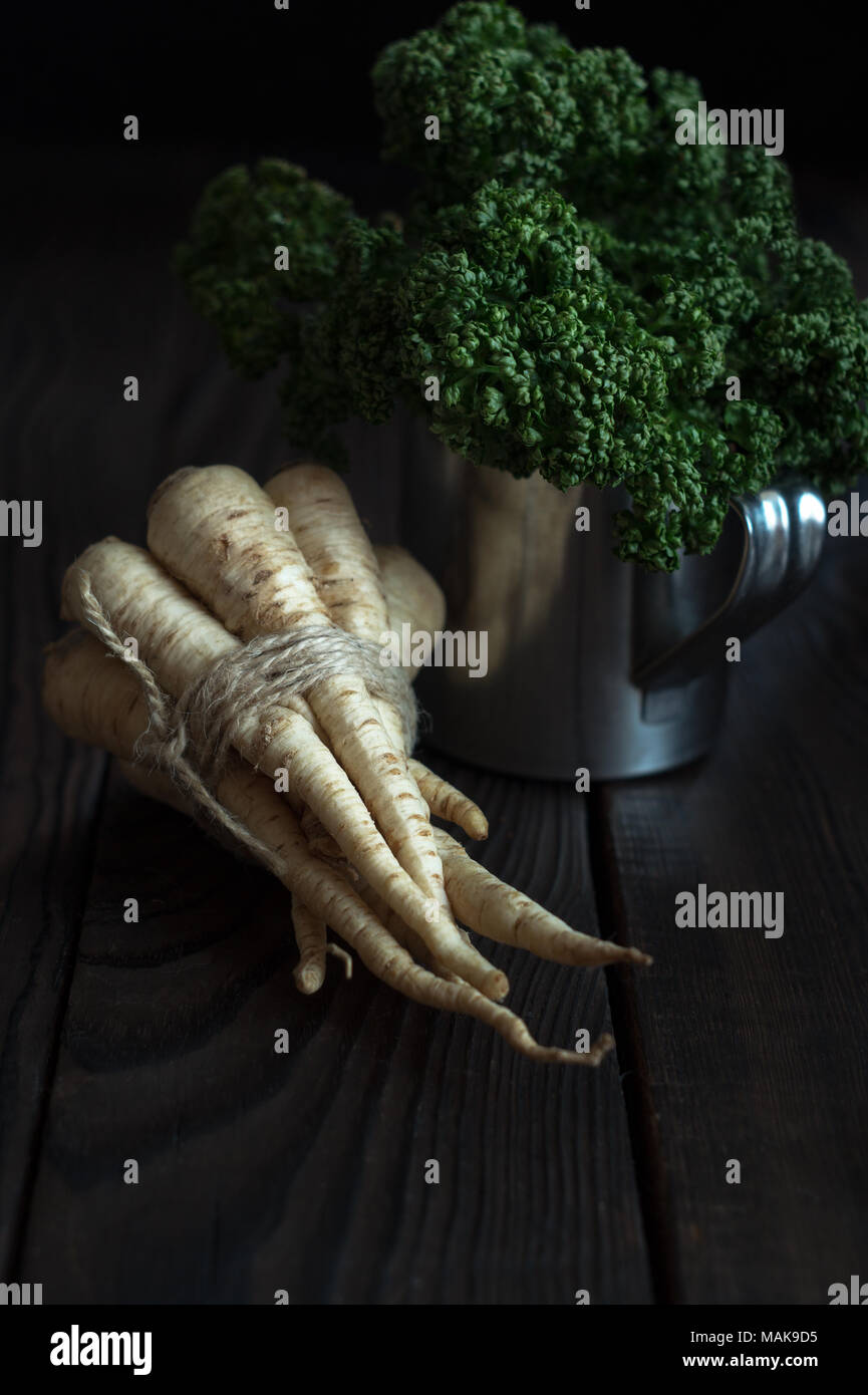 A bunch of roots and parsley on a dark wooden table Stock Photo - Alamy