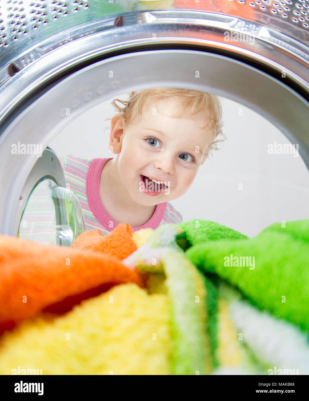 happy kid looking inside wash machine with clothes Stock Photo - Alamy
