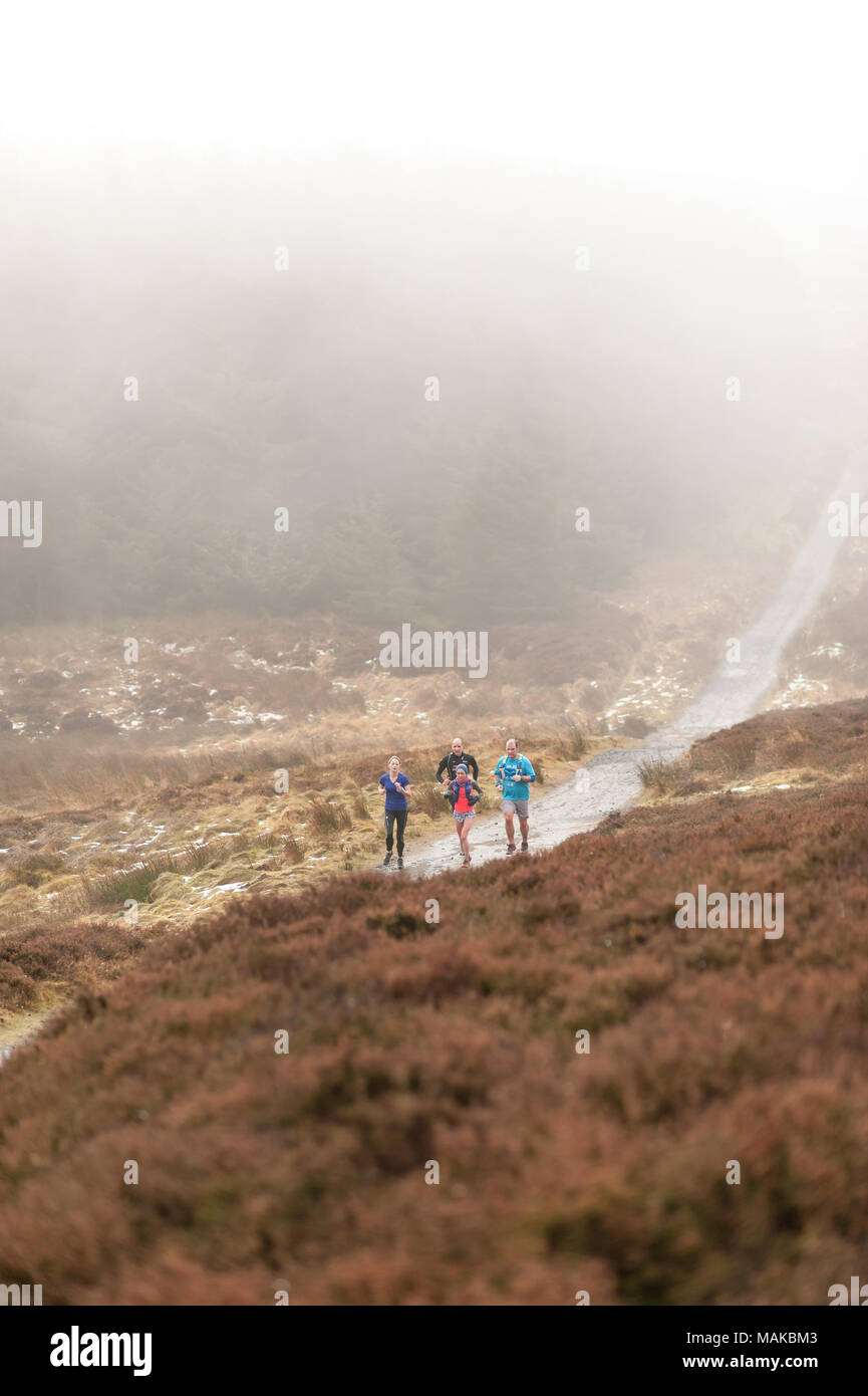 A mixed group of people running in a foggy day along a muddy path Stock ...