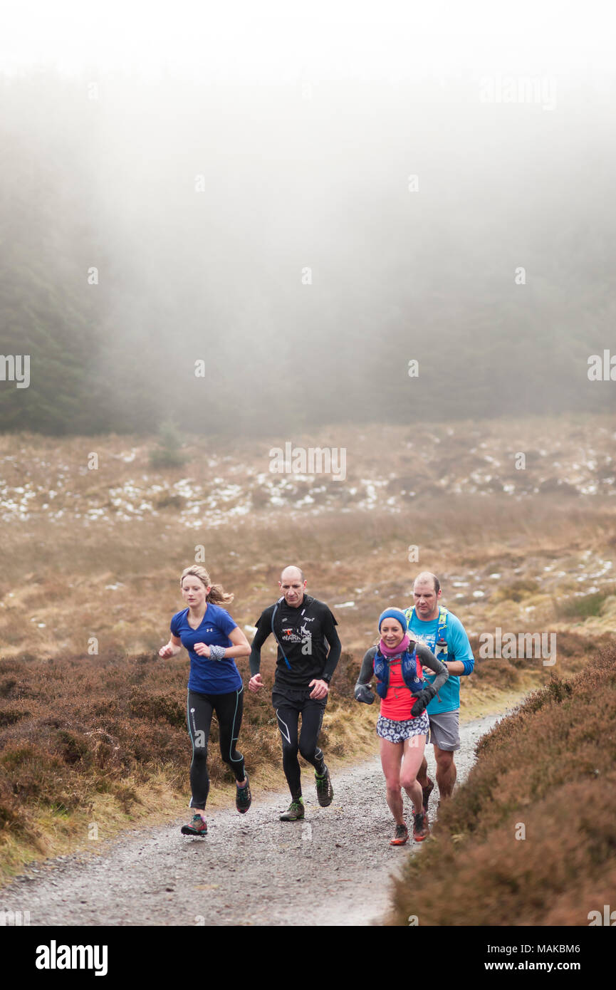 A mixed group of people running in a foggy day along a muddy path Stock ...