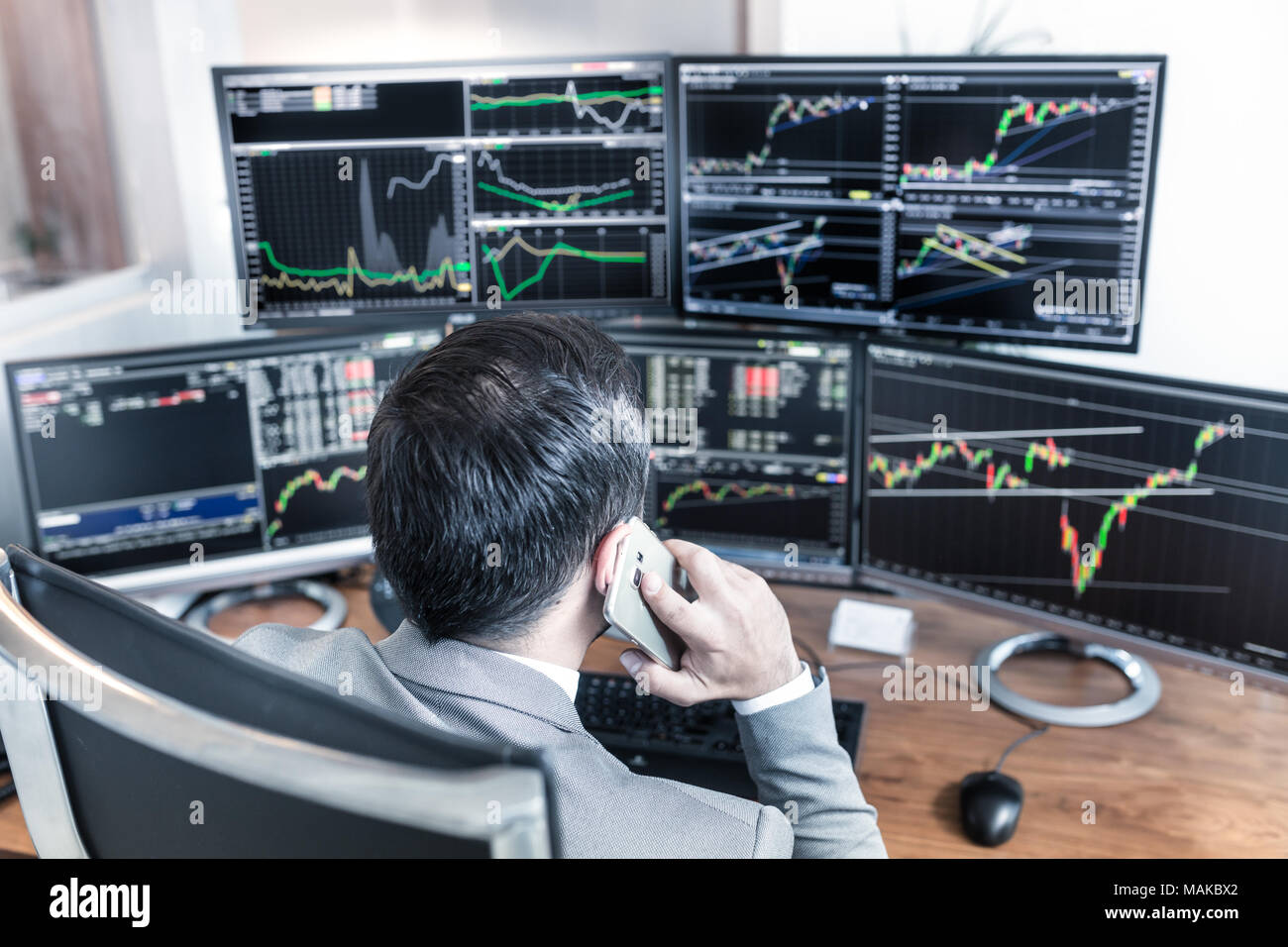 Over the shoulder view of computer screens and stock broker trading ...