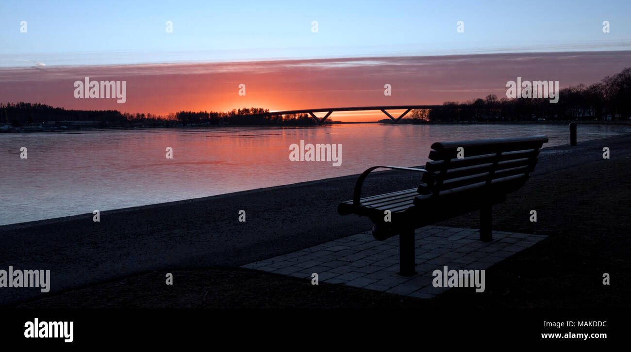 A bench overlooking a sunset behind a bridge Stock Photo - Alamy