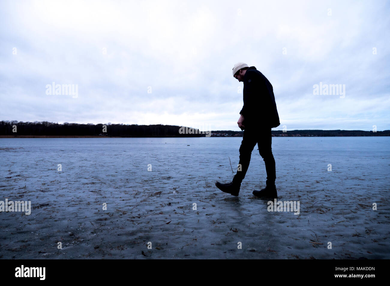 A young man walks across an icy lake with his head hanging down Stock ...