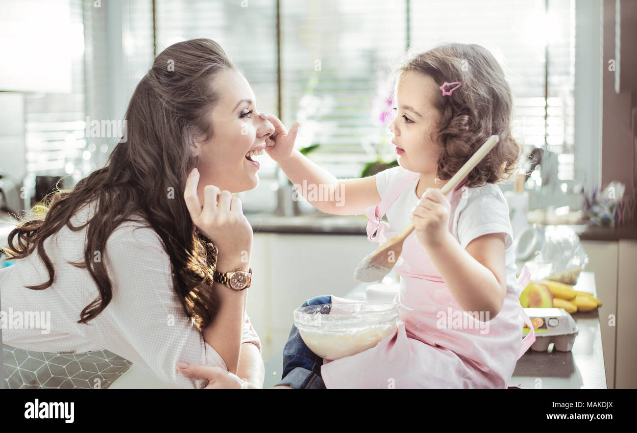 Pretty mother and her little daughter preparing a cake Stock Photo - Alamy