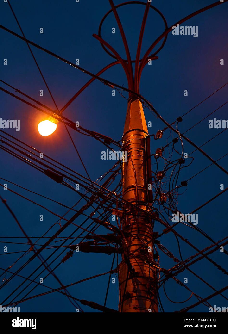 Big red street light surrounded by the web of power lines in the night ...