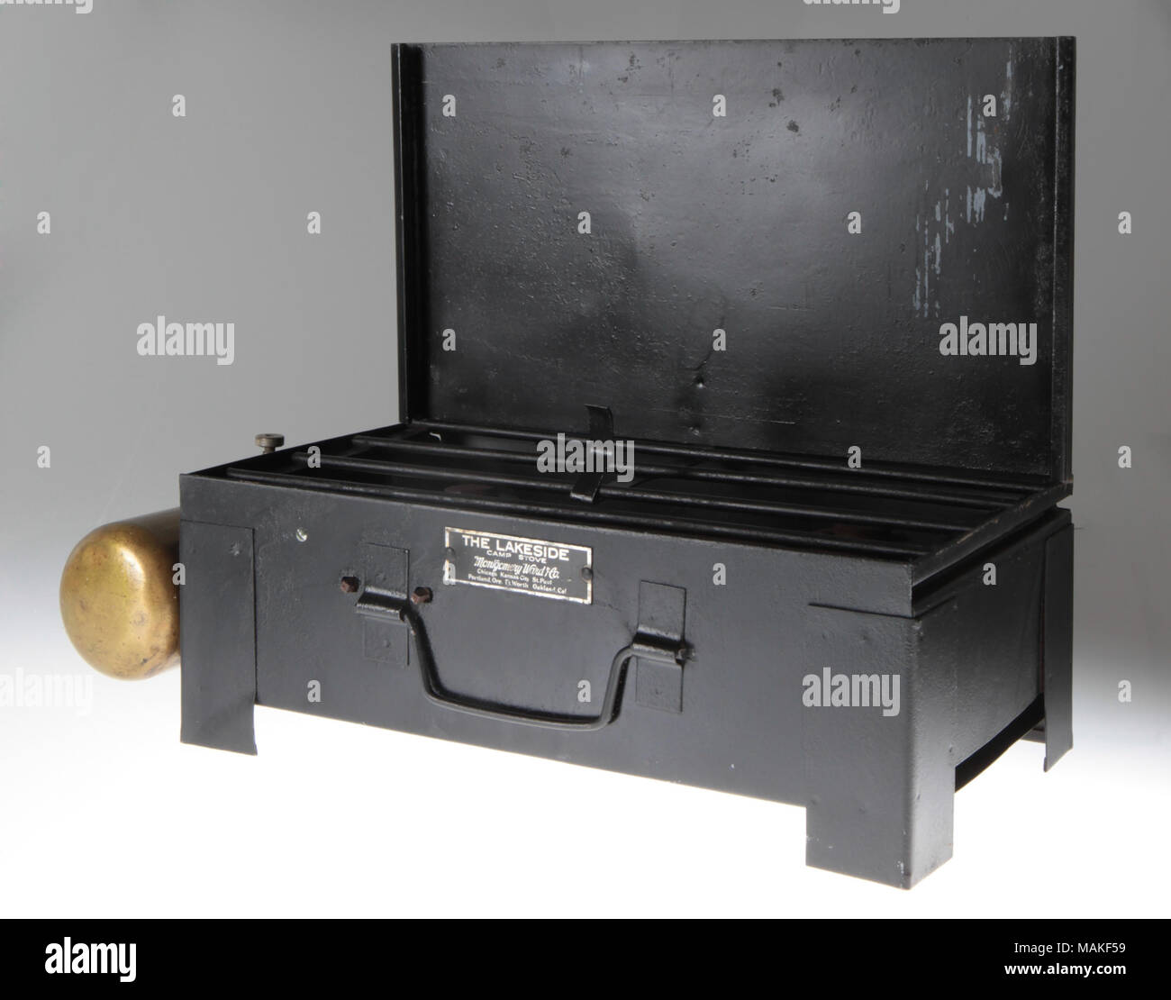 Portable gas stove with black exterior and brass fuel tank on the side ...