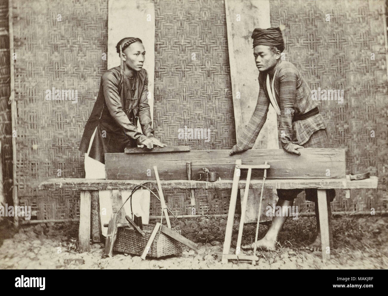 Indonesian men working on planing a log, Dutch East Indies. . between ...
