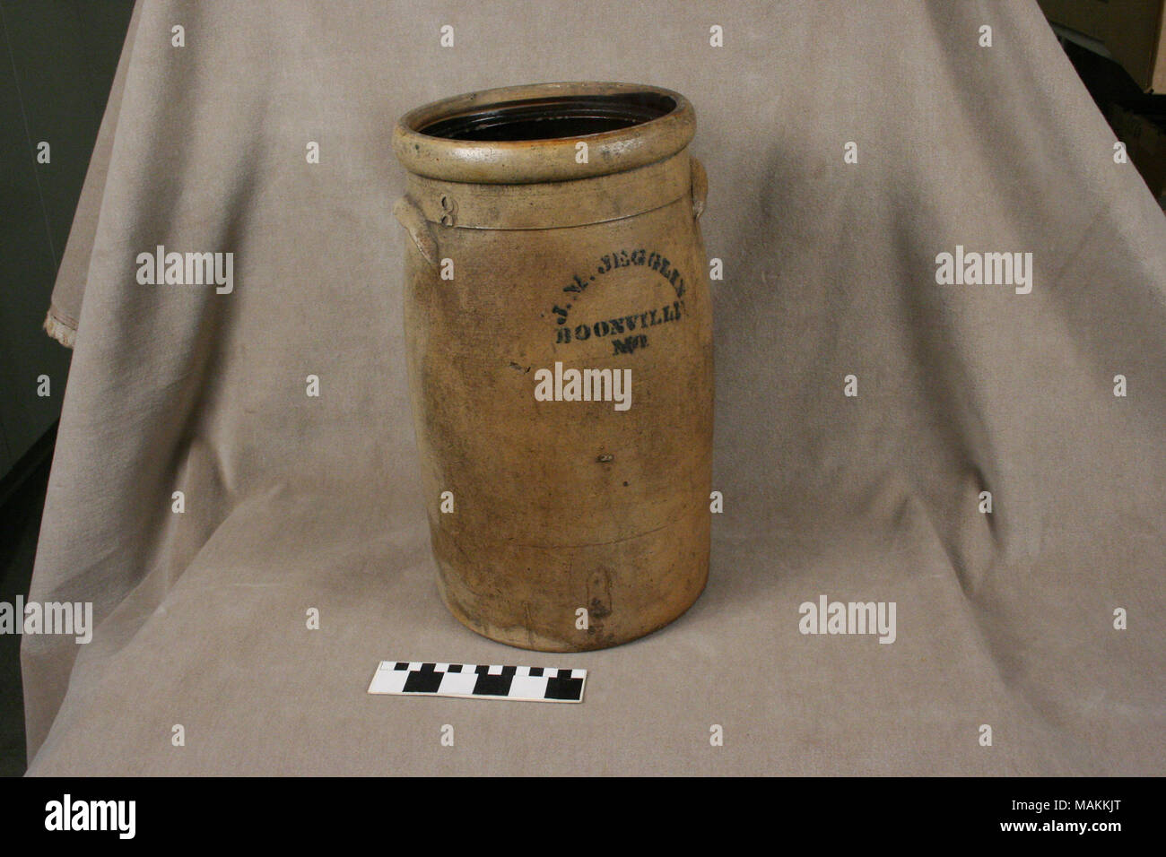 Tan ceramic churn with two molded lug handles. Body is cylindrical with ...