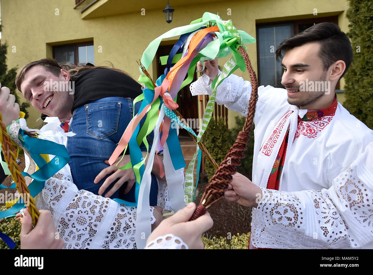 Young men in folk costume whip a girl with plaited willow stems during Easter Monday traditional ...
