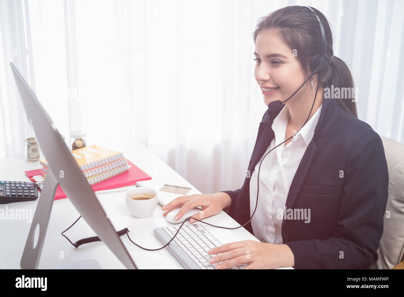 Young beautiful girl working at a laptop in a small medium enterprise ...