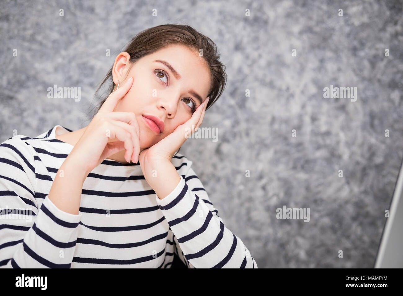 Beautiful young woman looking at a computer screen and thinking at the ...