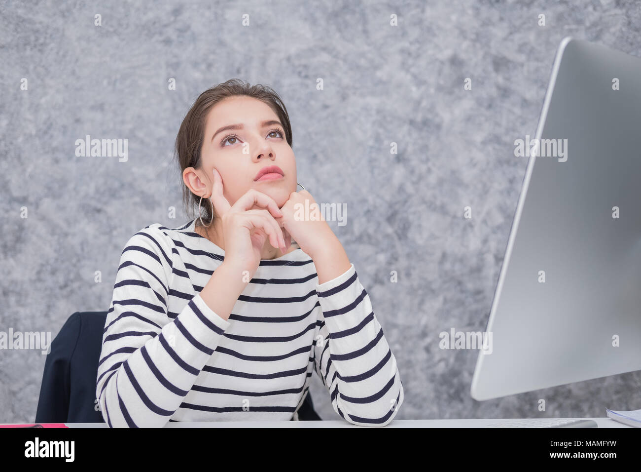 Beautiful young woman looking at a computer screen and thinking at the ...