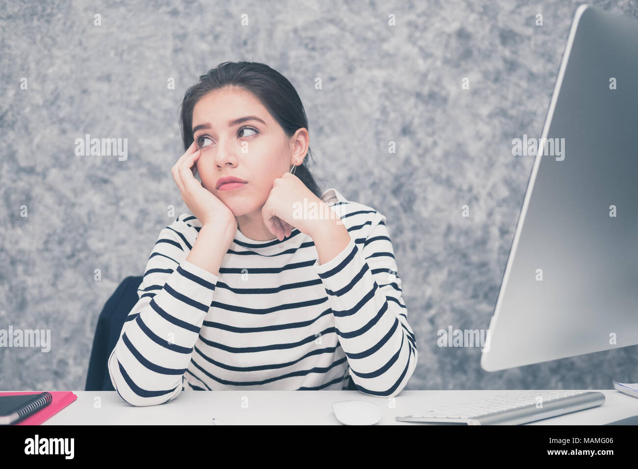 Beautiful young woman looking at a computer screen and thinking at the ...