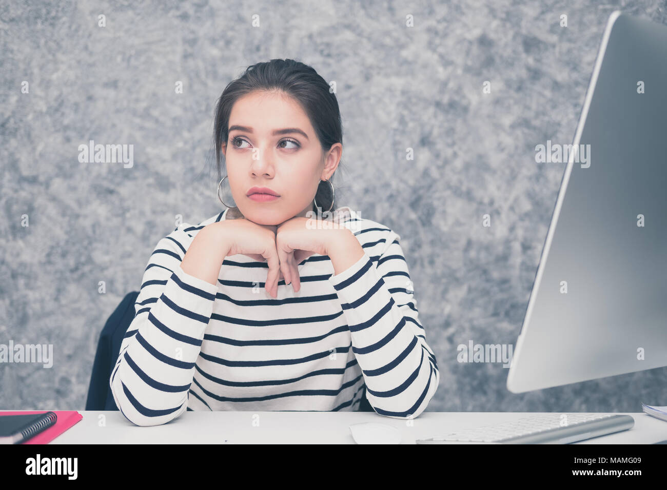 Beautiful young woman looking at a computer screen and thinking at the ...