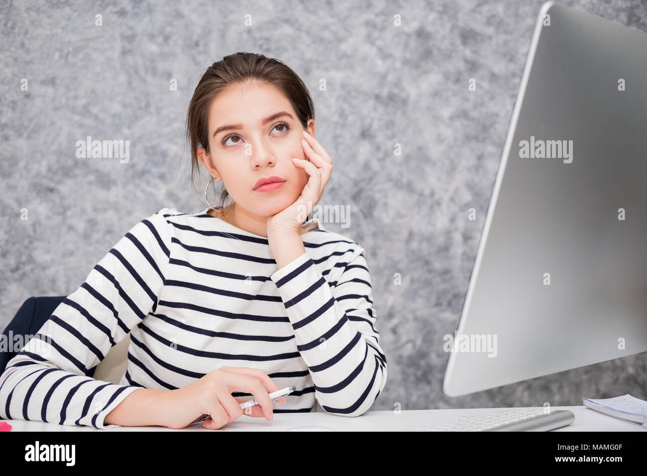 Beautiful young woman looking at a computer screen and thinking at the ...