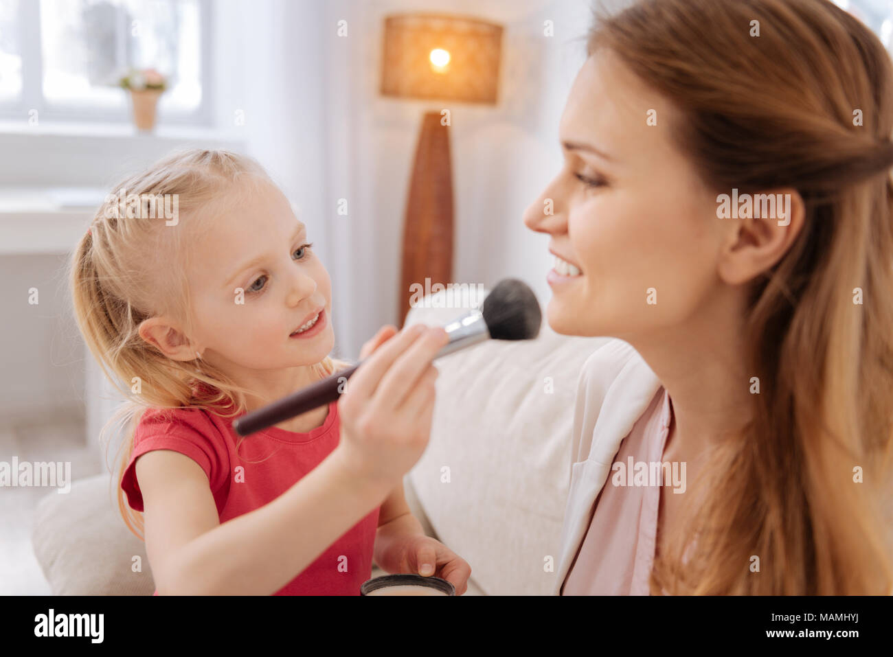Positive skillful girl putting powder on her mothers face Stock Photo ...