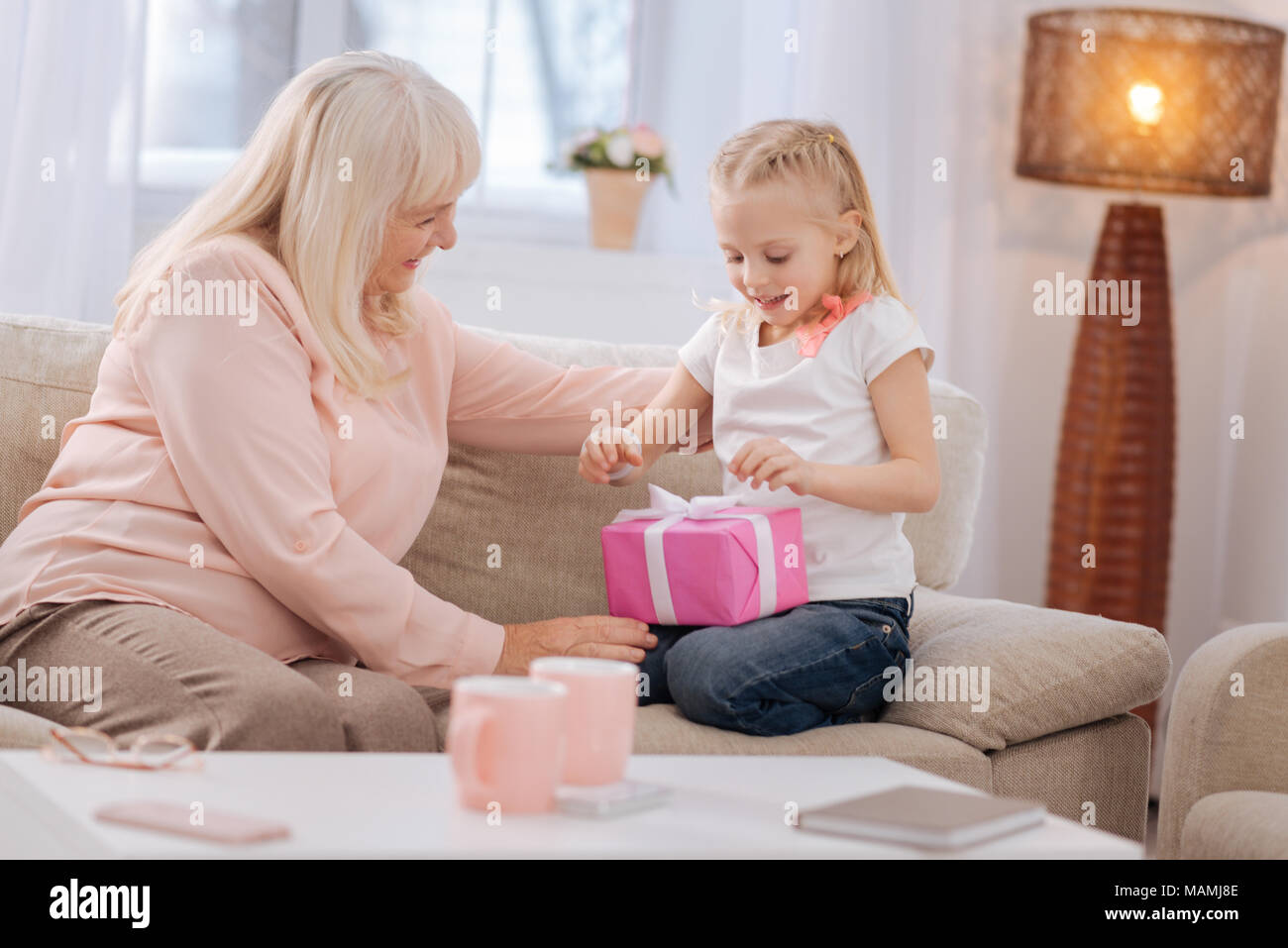 Pretty excited girl opening her present Stock Photo - Alamy