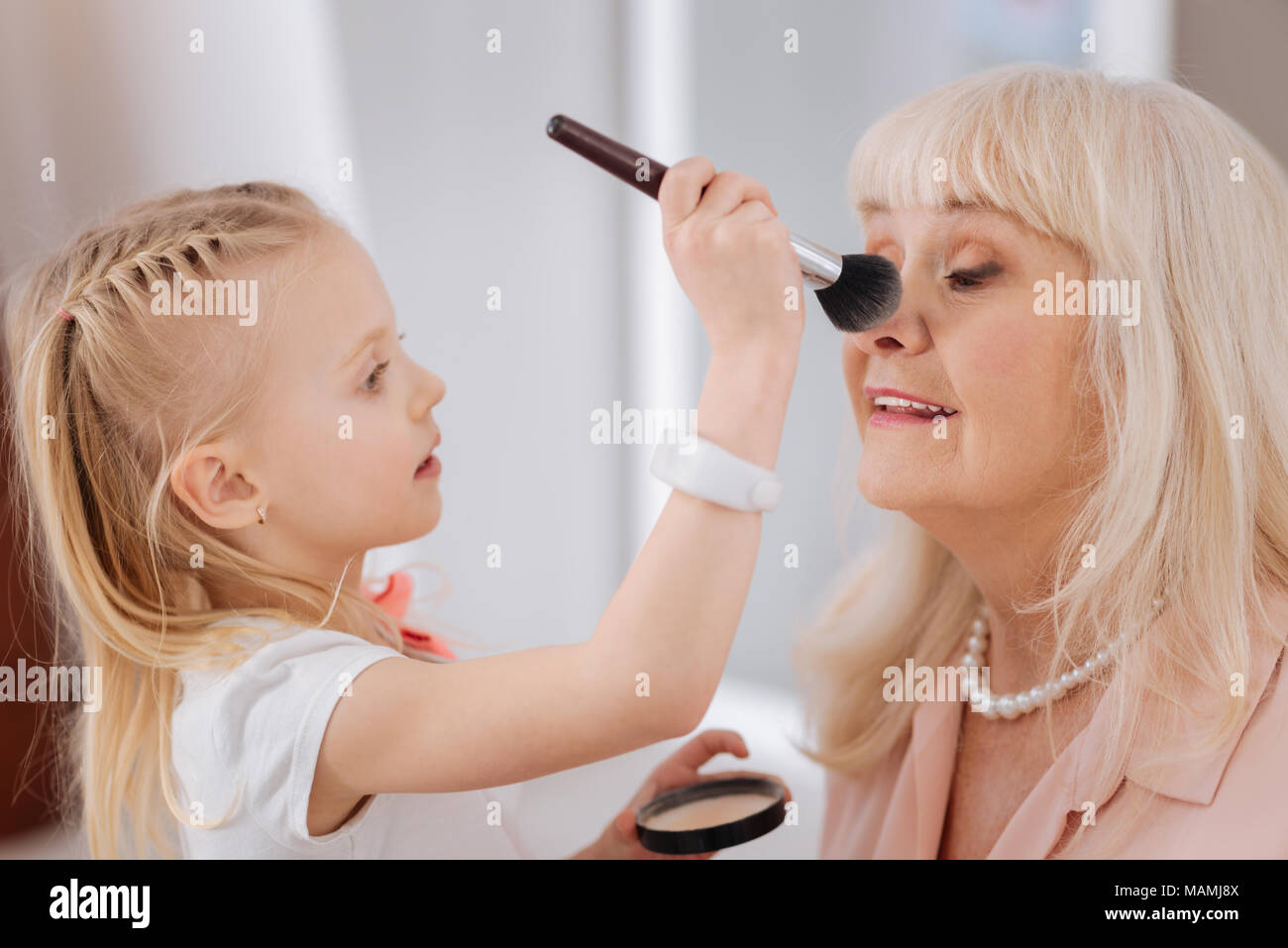 Cute pretty girl putting powder on her grandmothers nose Stock Photo ...