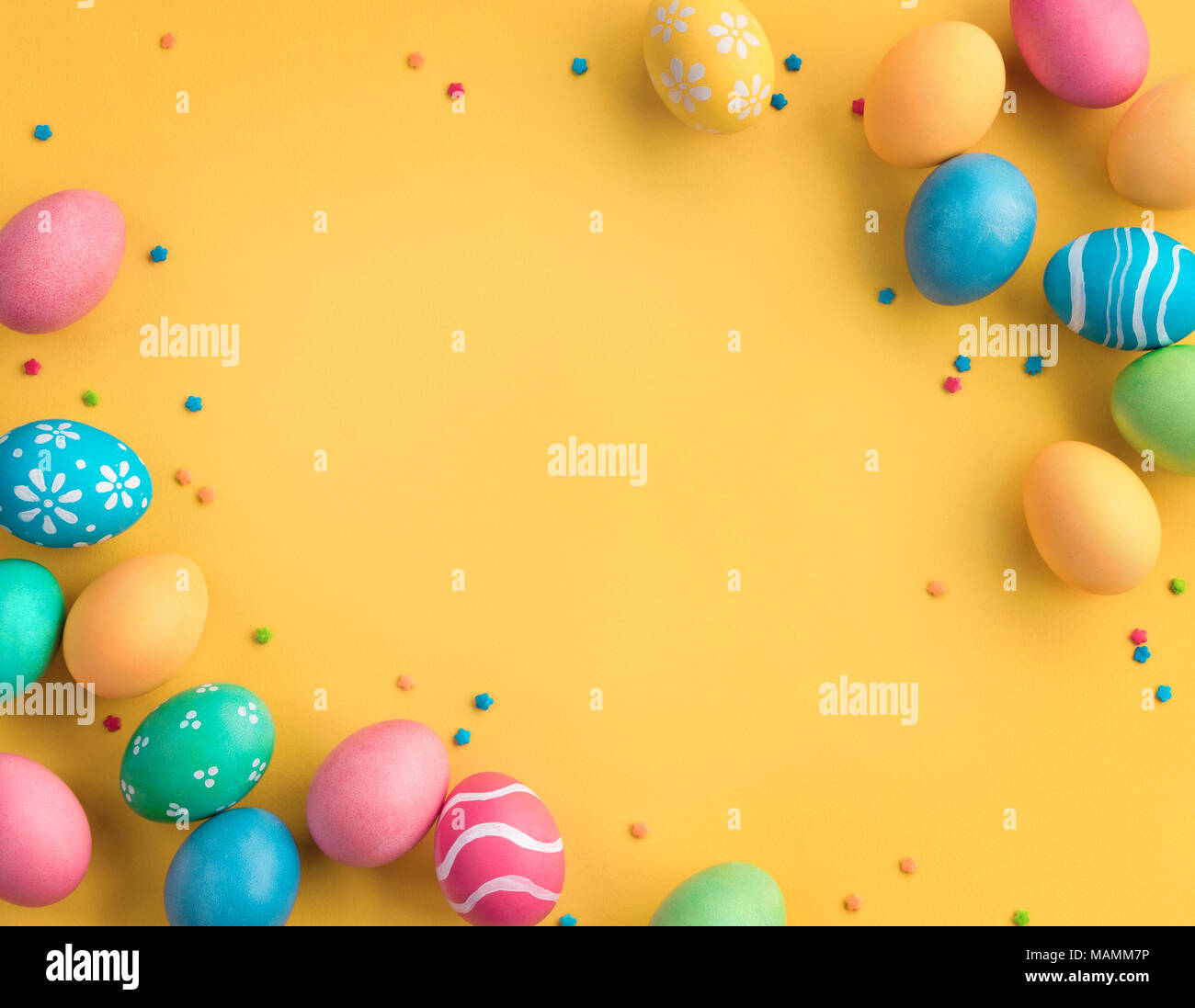 Happy Easter! Yellow background with colorful easter eggs. Top view ...