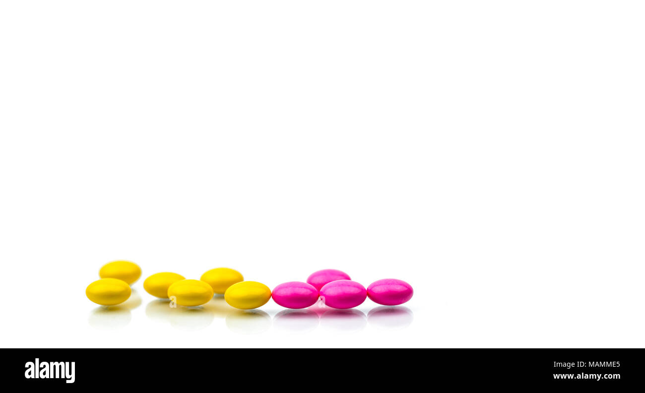 Pile of pink and yellow round sugar coated tablets pills isolated on ...