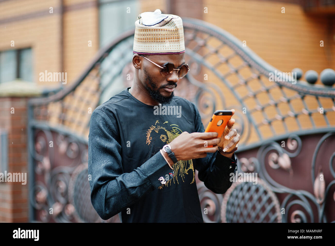 Rich african man in stylish traditional clothes and hat posed outdoor ...
