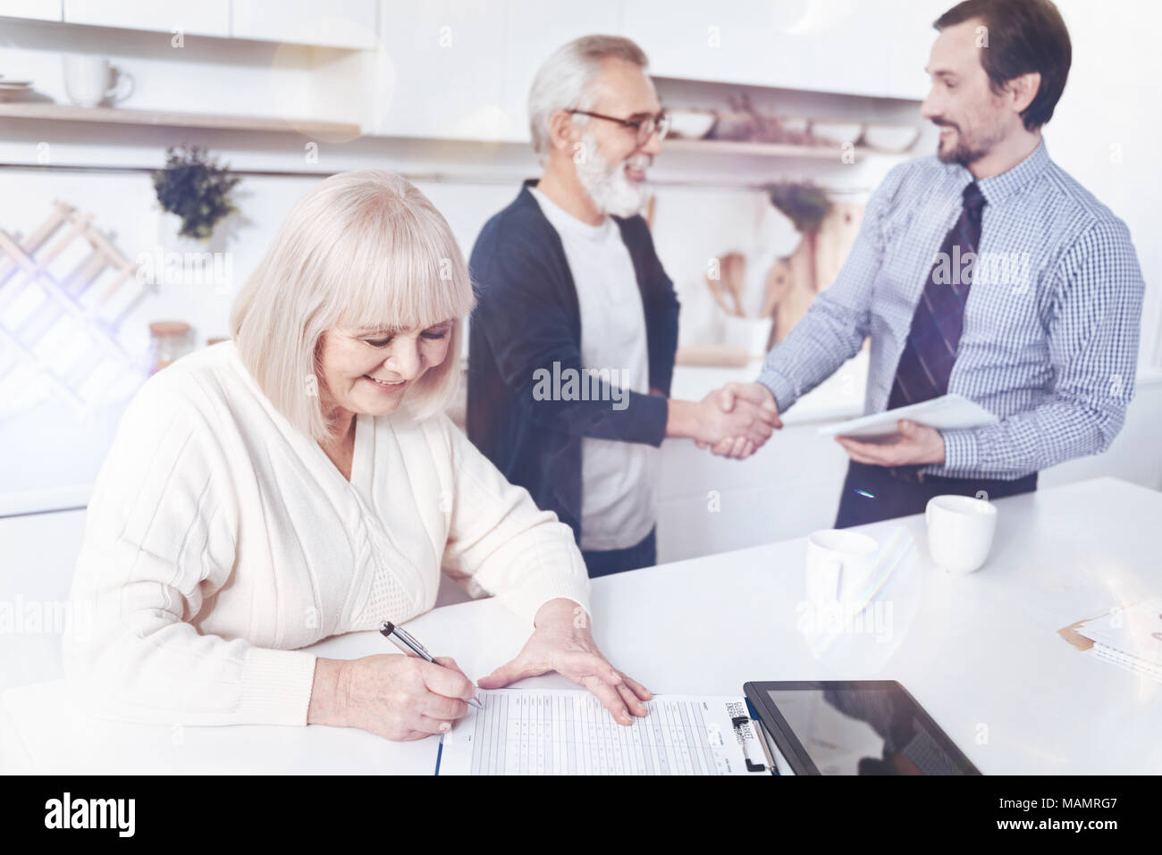 Positive smilign aged woman signing insurance contract Stock Photo - Alamy