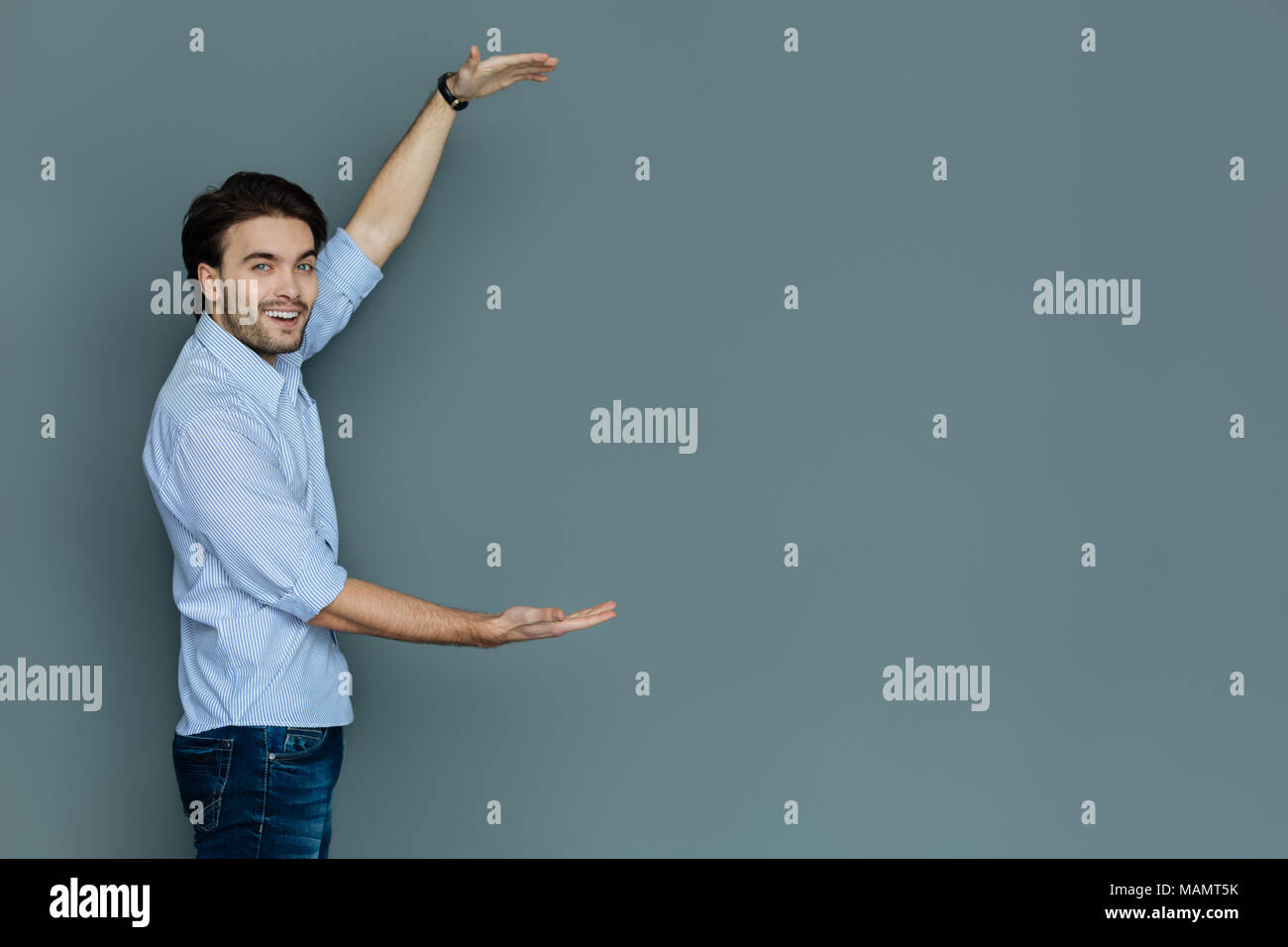 Delighted positive man showing the size of an object Stock Photo - Alamy