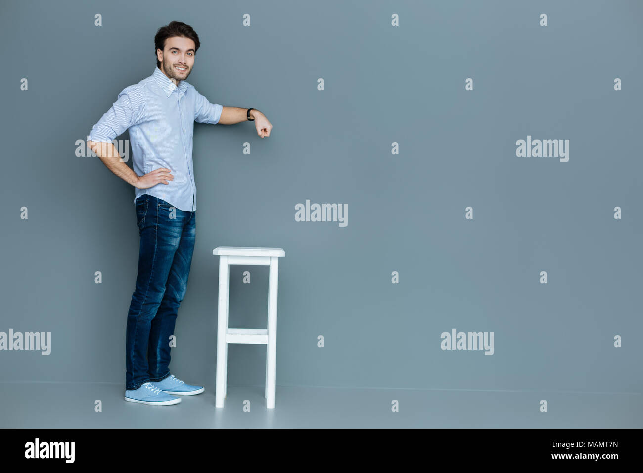 Nice handsome man standing near the stool Stock Photo - Alamy